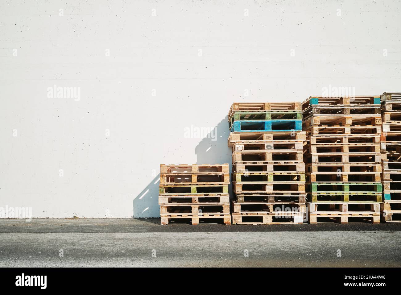 Stacked pallets at wall in backyard Stock Photo - Alamy