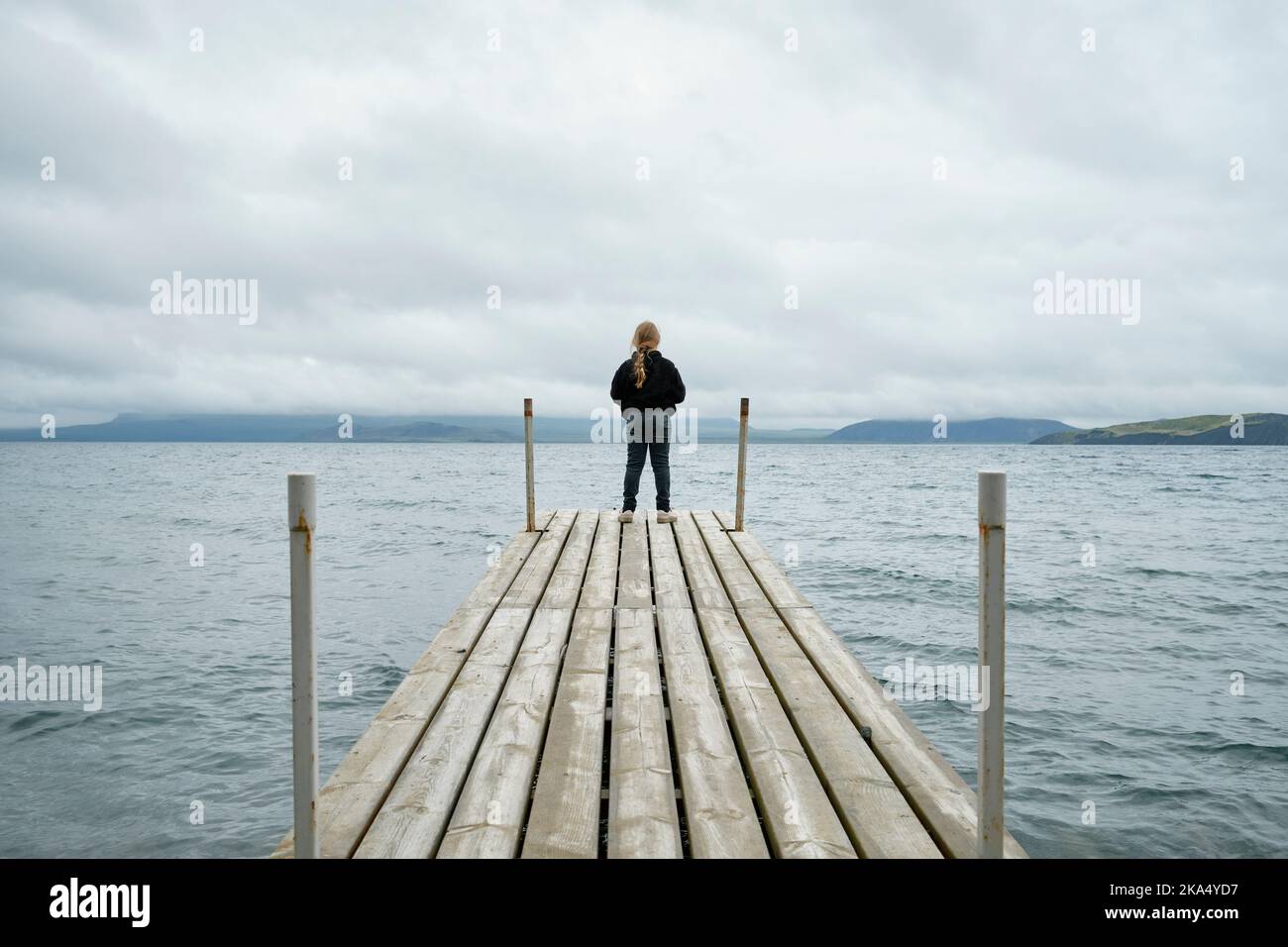 Anonymous girl standing on quay on overcast day Stock Photo - Alamy