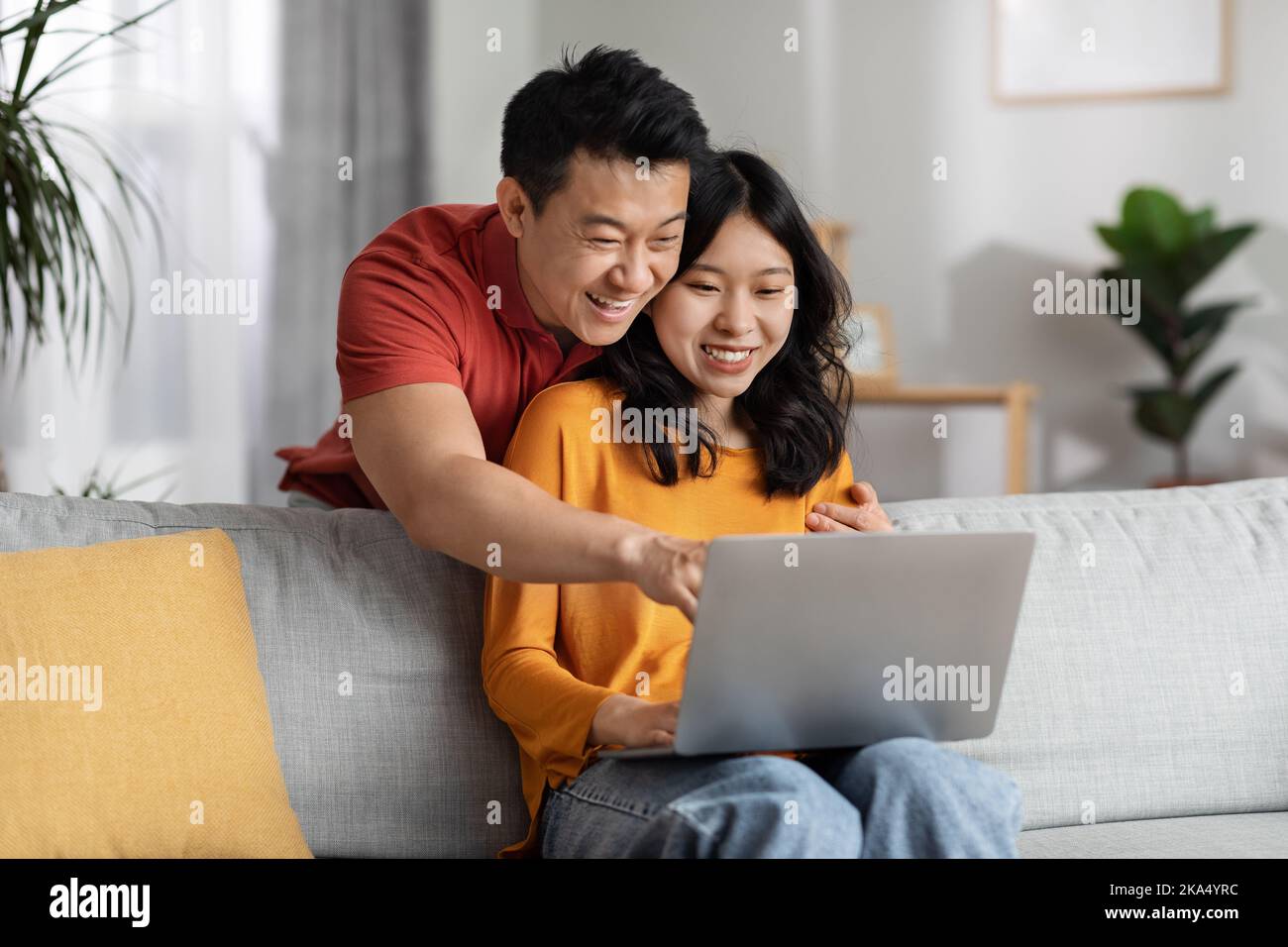 Positive korean man and woman using computer at home Stock Photo - Alamy