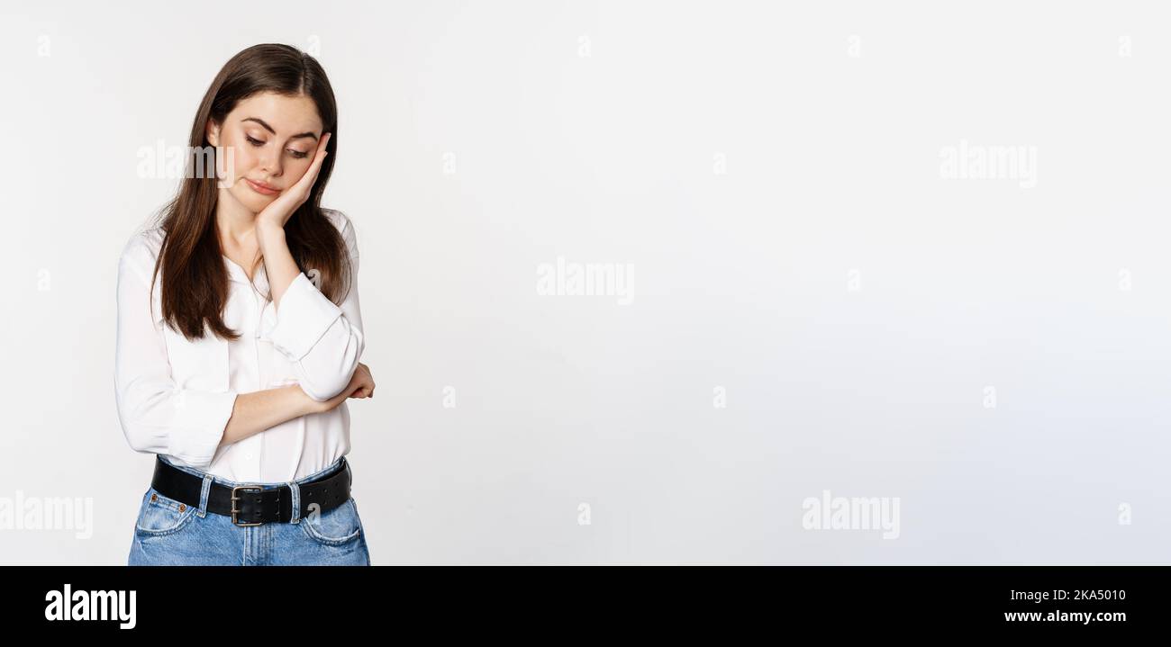 Unamused, bored brunette woman looking gloomy and sad, sighing ...