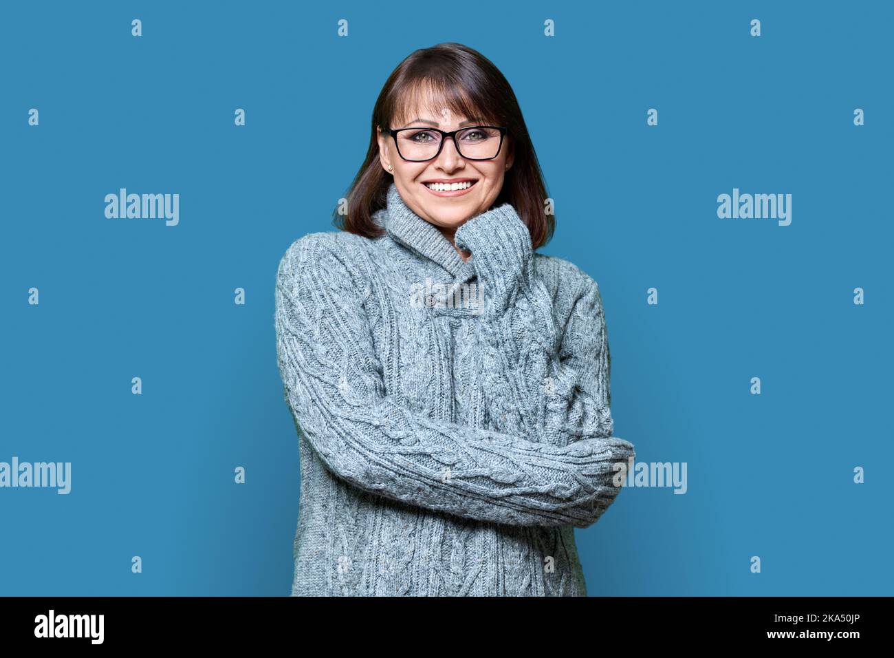Portrait of smiling middle aged female looking at camera on blue ...