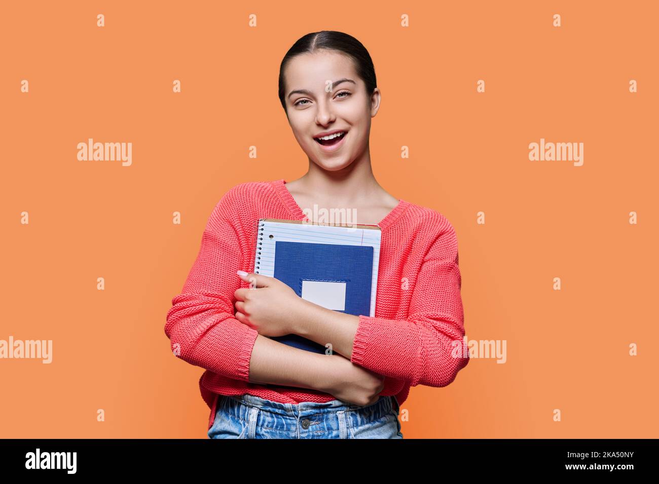 Portrait of teenage high school student on on orange color studio ...