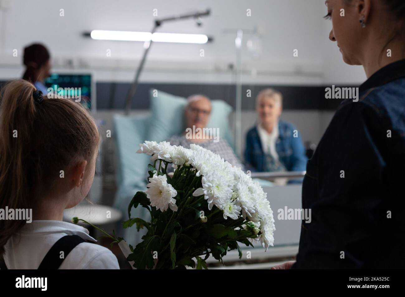 Unrecognizable Girl Holding Grandfather Flowers While Frican American Doctor Performs Routine
