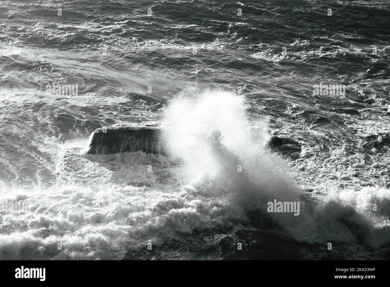 Black and white photo waves crashing against a large rock along the ...
