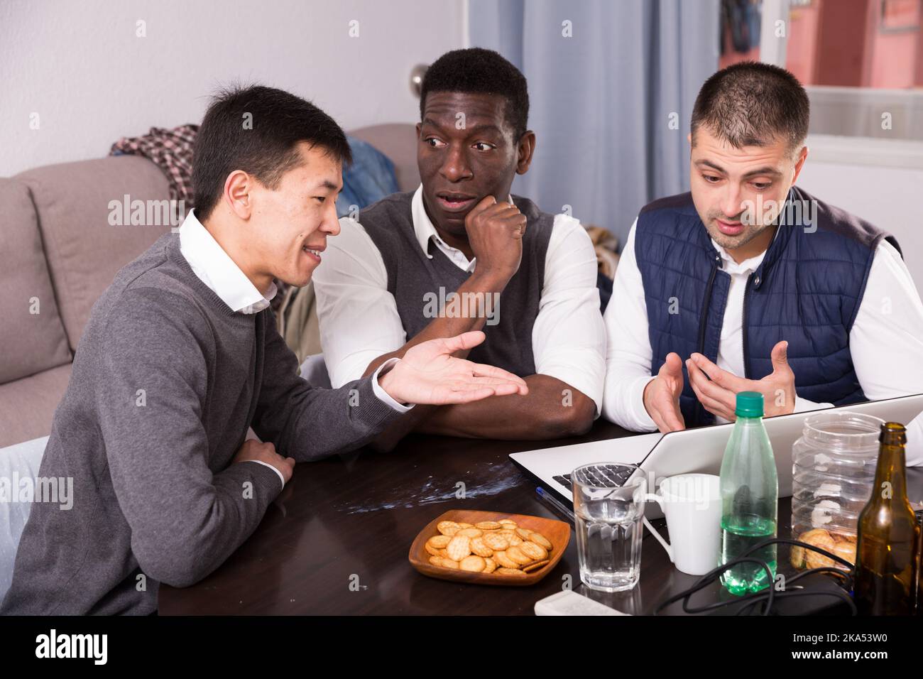 Three surprised men are talking about video and resting with food Stock ...