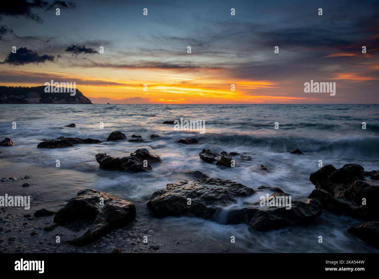 A long exposure seascape of waves washing over rocks on the beach in ...