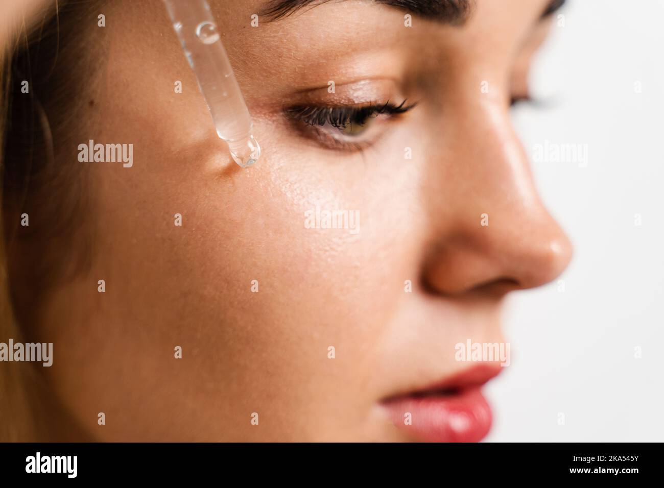 Girl drips facial serum on her cheek for acne treatment and wrinkle ...