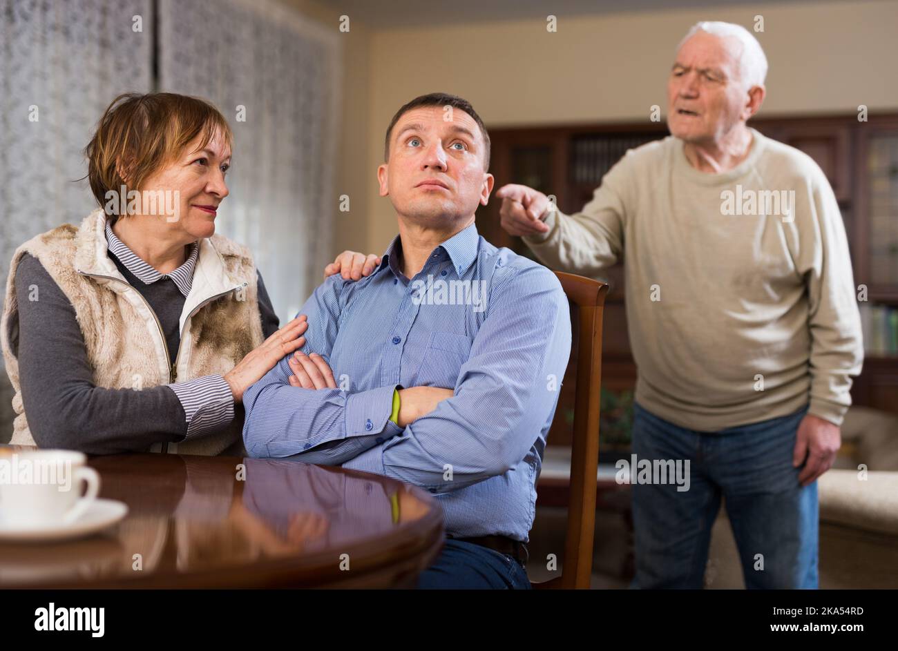 Mother calming adult son during quarrel with father Stock Photo - Alamy
