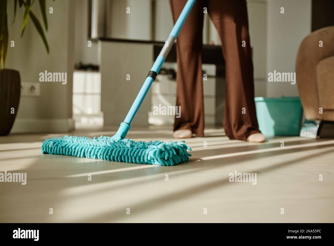 Close up of unrecognizable young woman mopping floors of light wood in ...