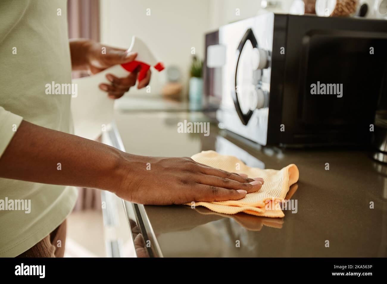 Close up of black young woman wiping kitchen counters while cleaning ...