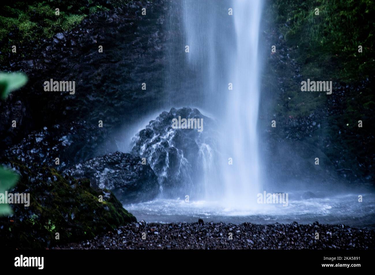 The bottom of the waterfall splashes the gravel and large boulder. Then ...
