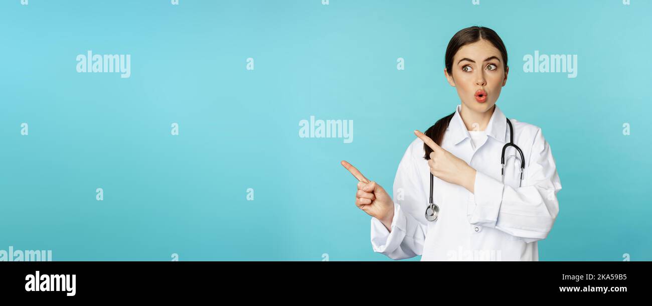 Surprised female doctor, physician with stethoscope, pointing and ...