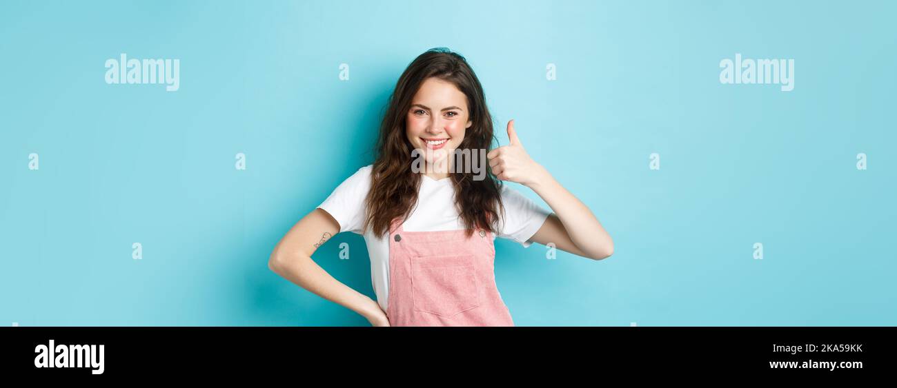 Portrait of confident and positive young woman show thumb up, say yes ...