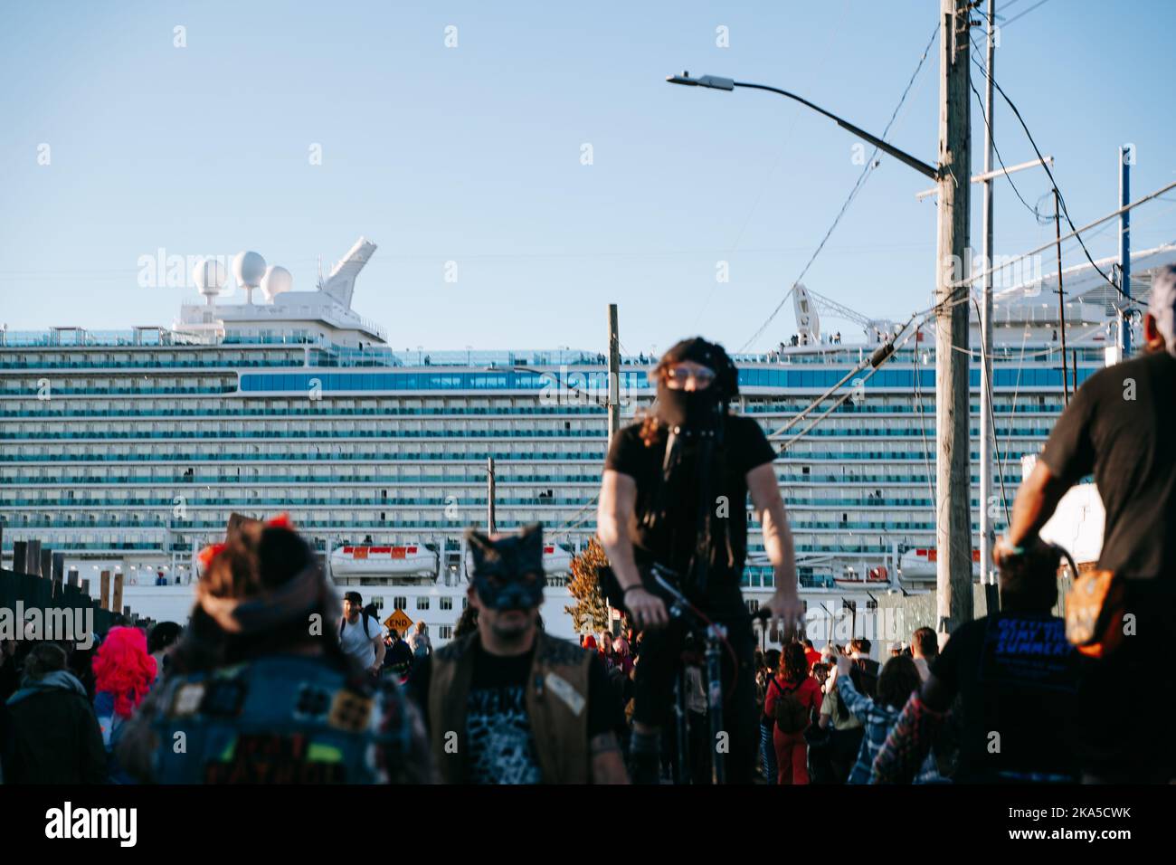 People look on from a cruise ships as hundreds of people ride modified ...