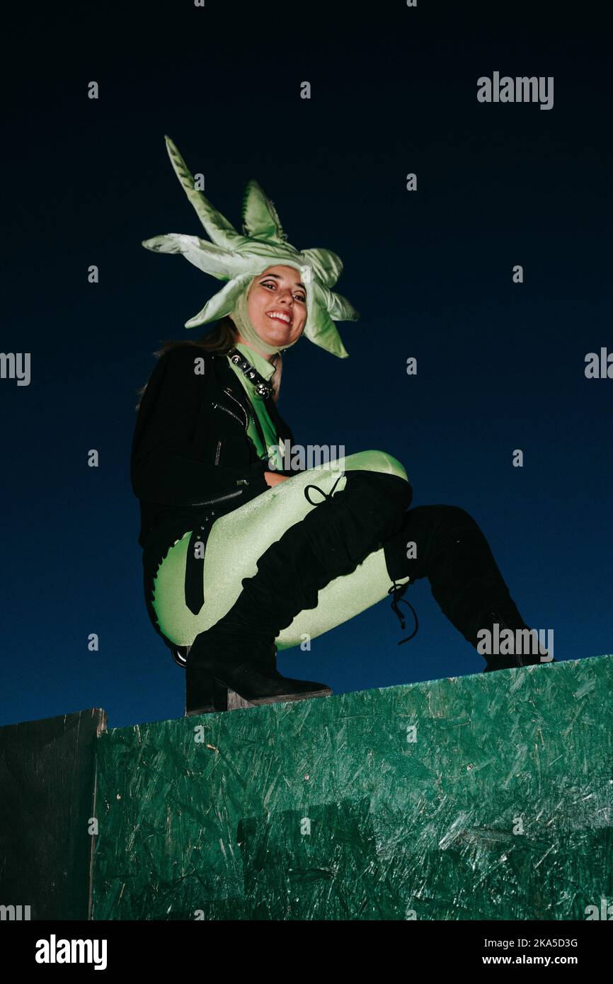 Woman dressed in a marijuana leaf costume climbs a fence to get a ...