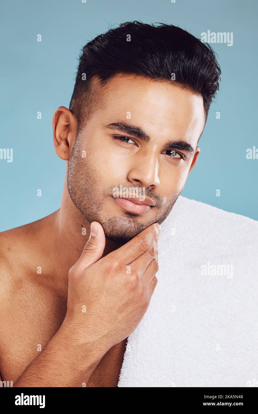 Hand, face and beauty with a man model posing in studio on a blue ...