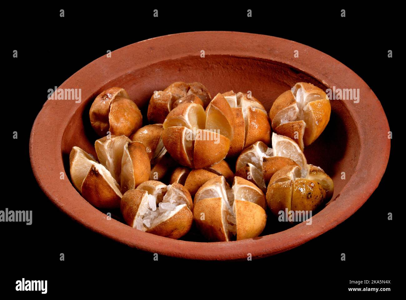 lime pickles in a clay pot, lime preserving process with salt, closeup ...
