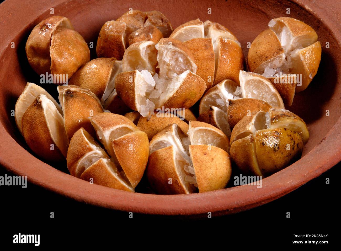 lime pickles in a clay pot, lime preserving process with salt, closeup ...