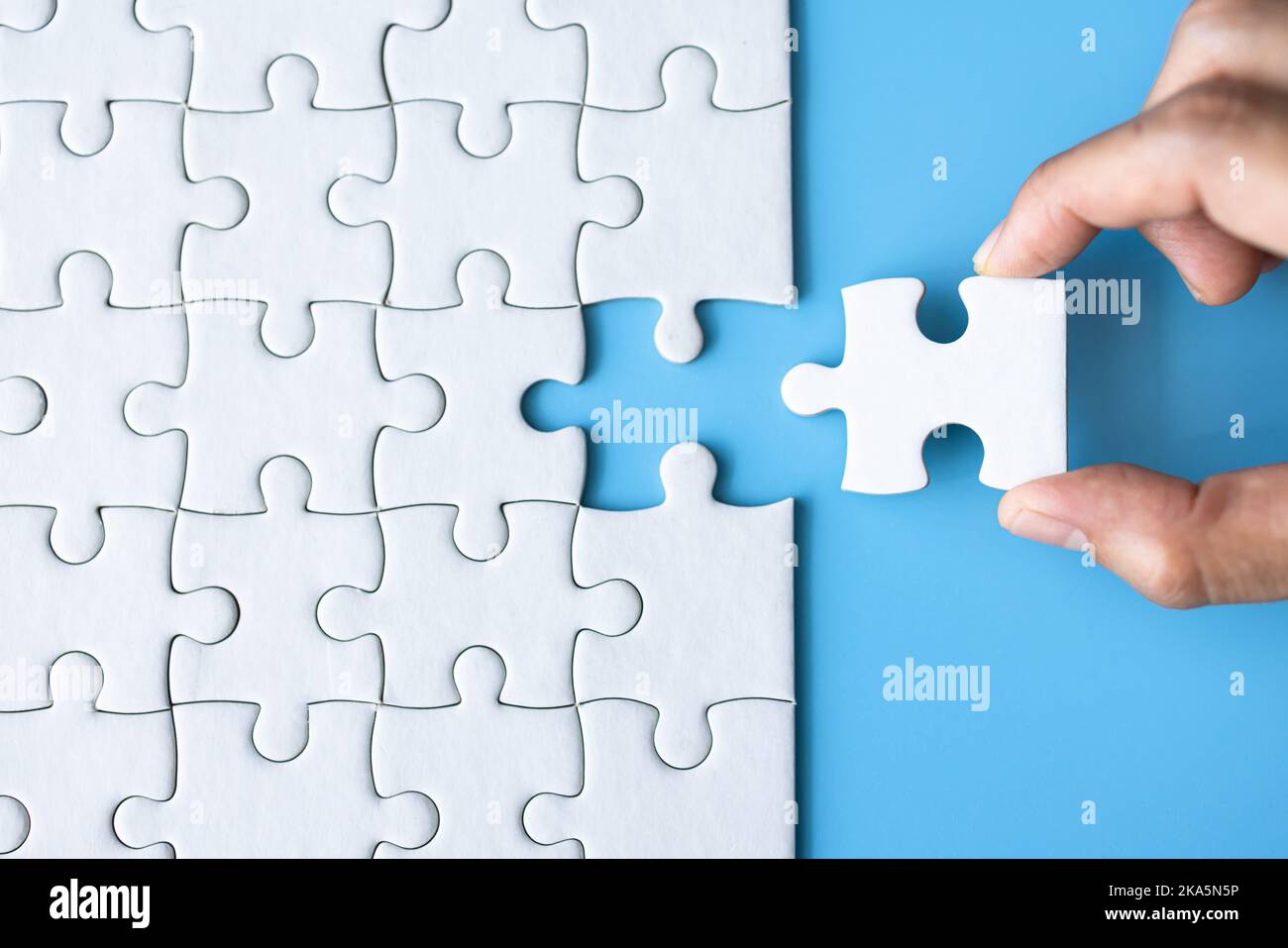 Hand put the last piece of jigsaw puzzle to complete the mission ...