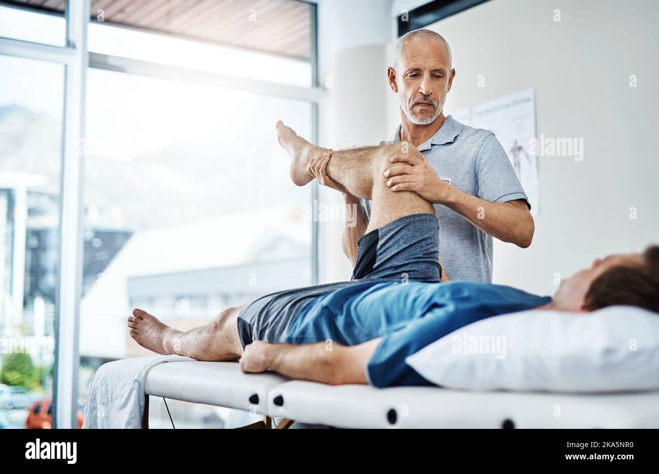 Tell me where youre feeling the pain. a physiotherapist treating a ...