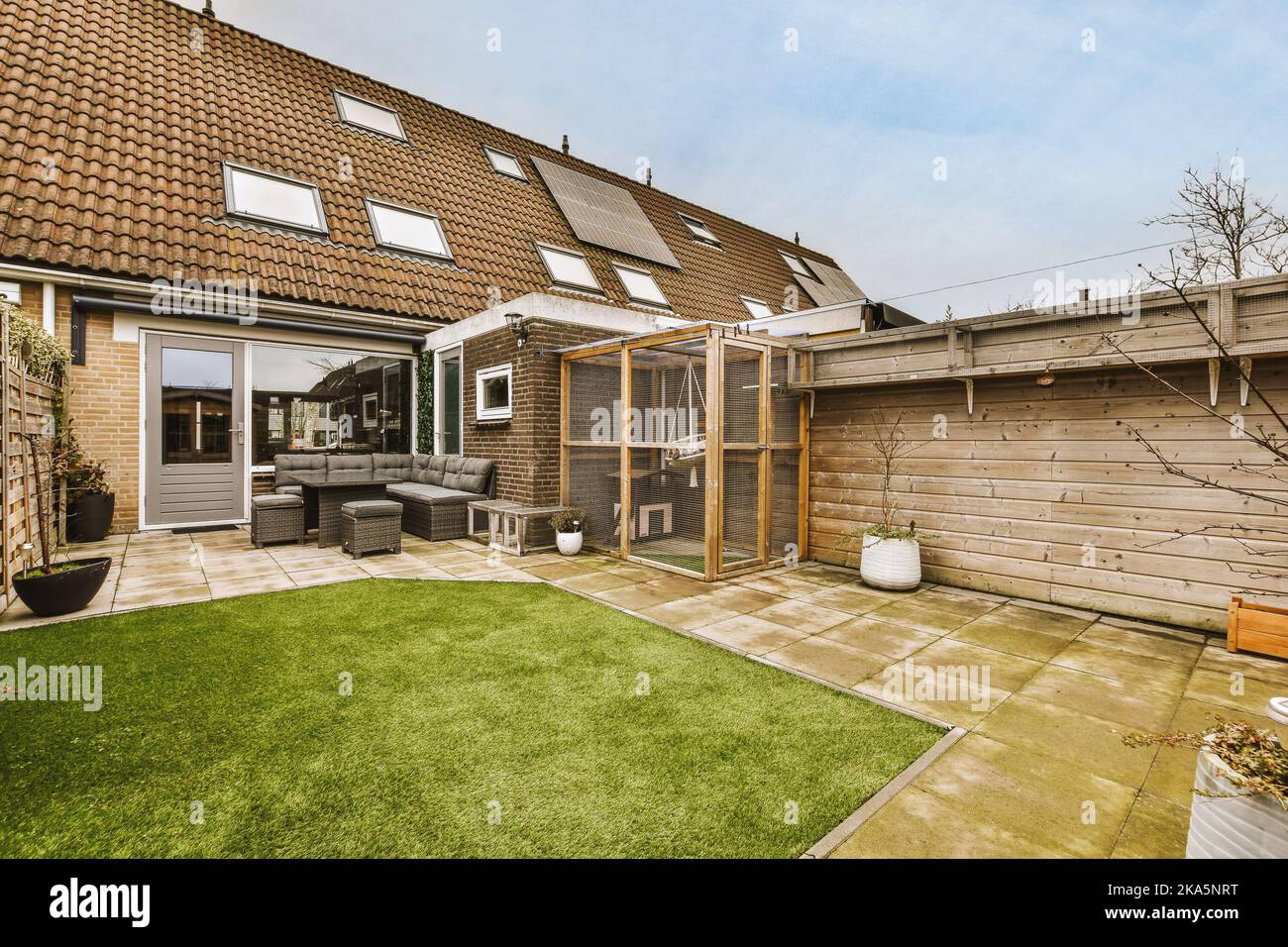 Neat paved patio with sitting area and small garden near wooden fence ...