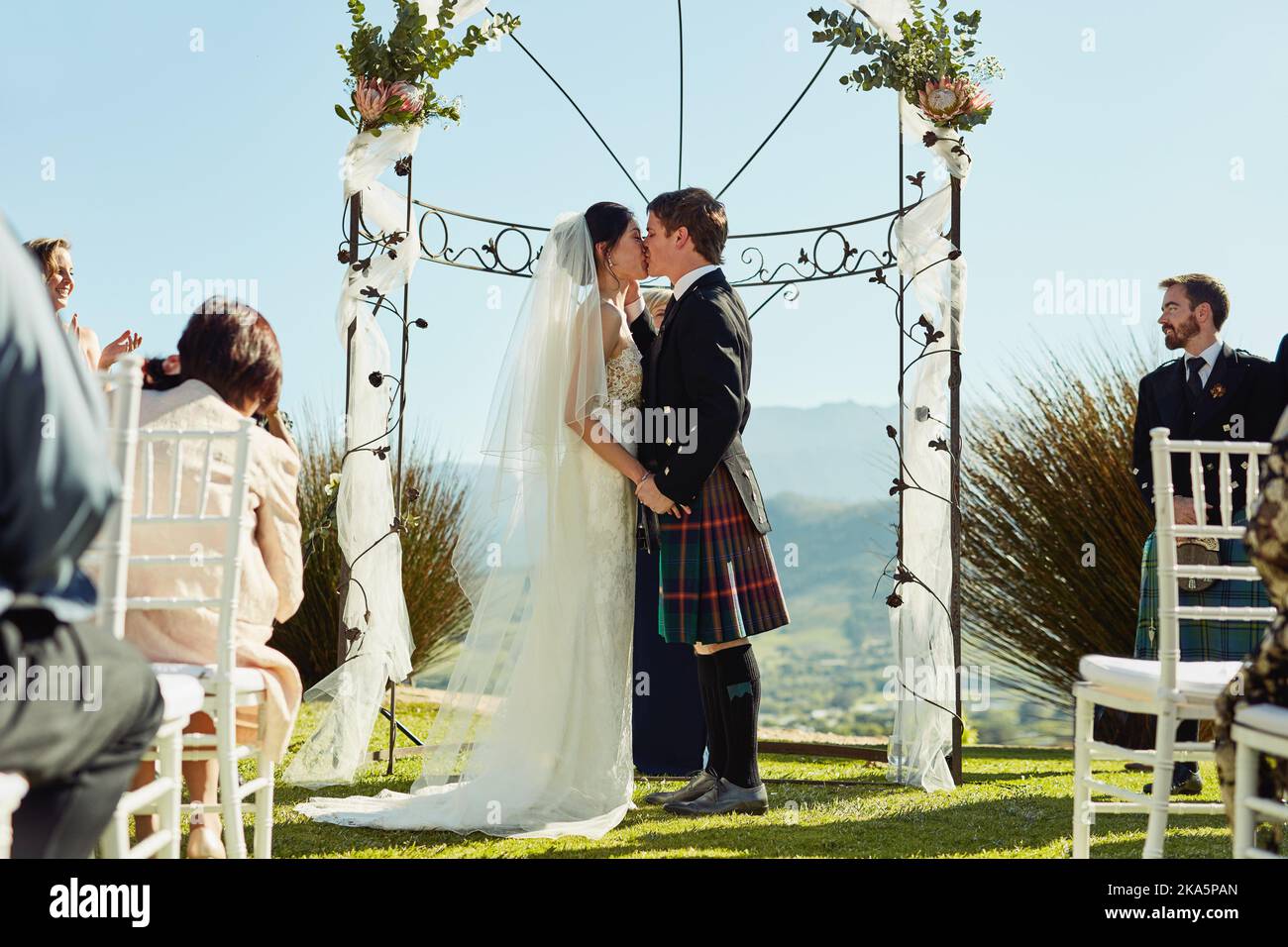 You may kiss the bride. a cheerful young bride and groom sharing a kiss ...