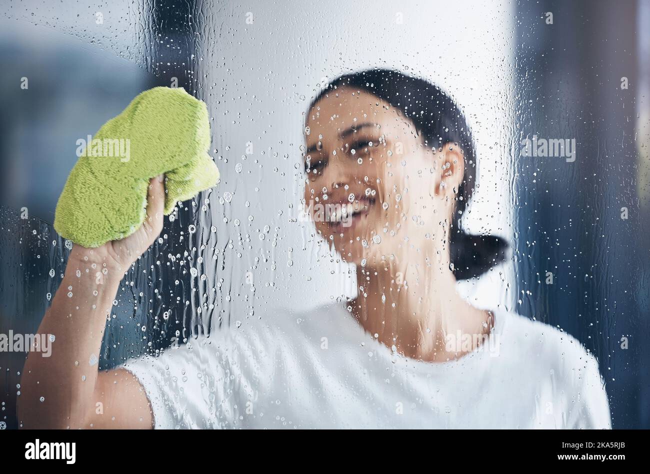 Cleaning, washing window and woman with cloth in hand to wipe water ...
