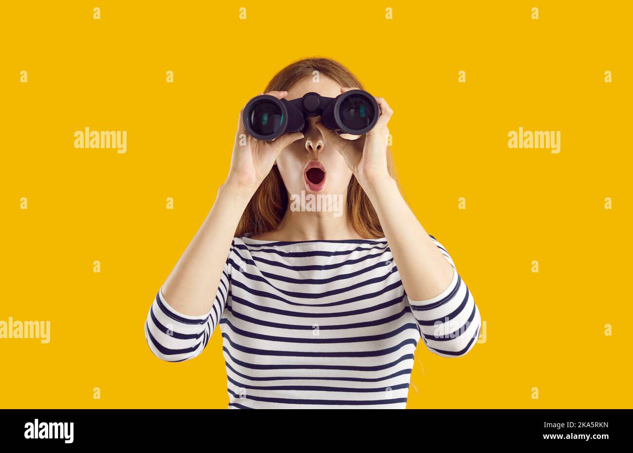 Curious and inquisitive woman peeking through binoculars with shocked ...