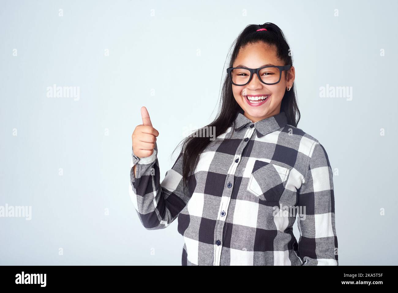 Hey Good job. Studio portrait of a cute young girl giving thumbs up ...