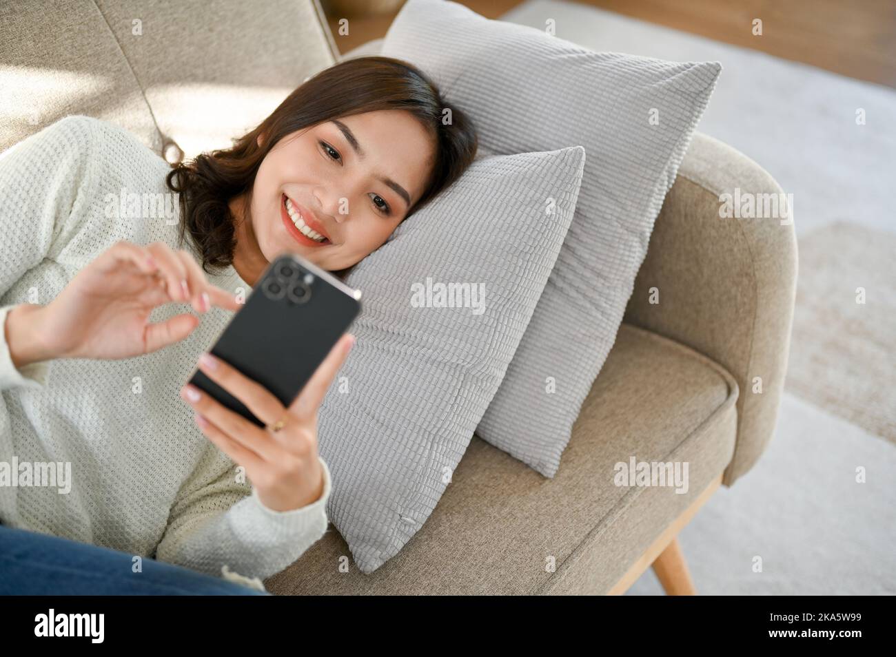 Attractive and happy young Asian woman in casual clothes lying on her ... Attractive and happy young Asian woman in casual clothes lying on her ...