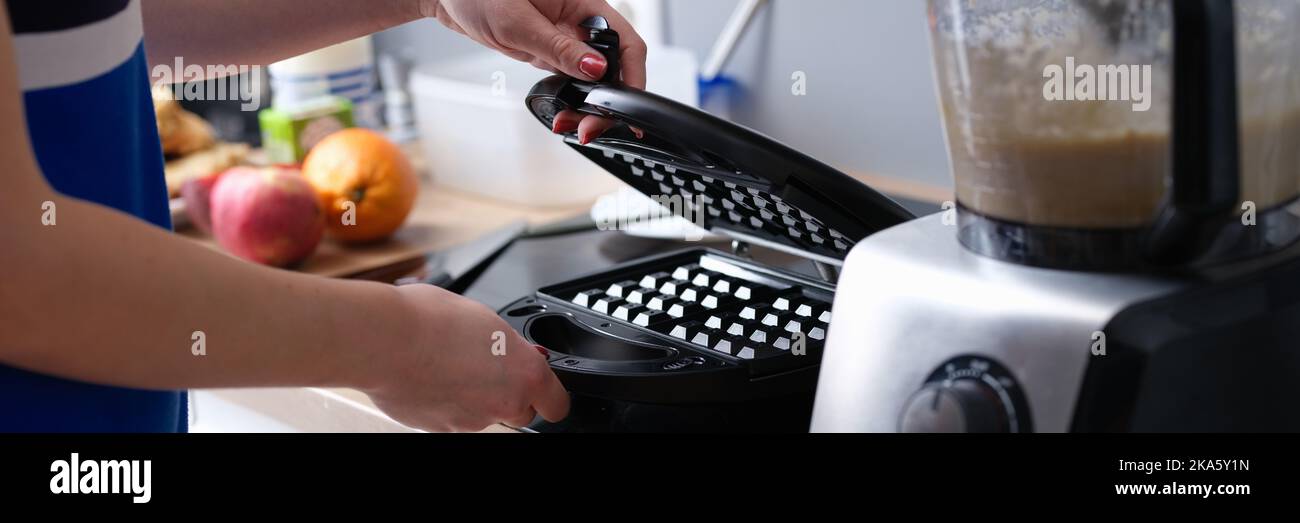 Woman opens electric waffle maker for Viennese and Belgian waffles ...