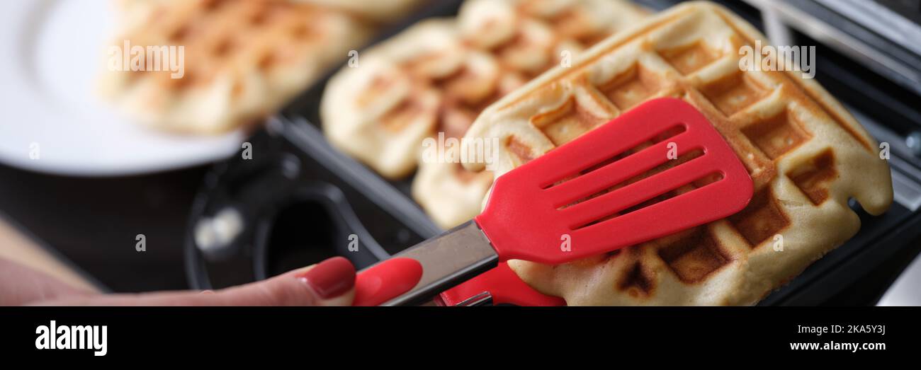 Female hands finishing making waffles on waffle iron in bakery Stock ...