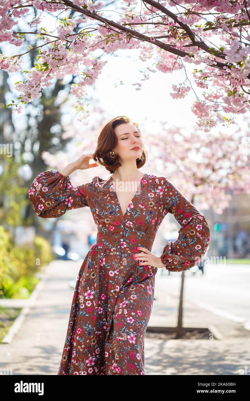 Beautiful young woman in a dress in blooming sakura trees. It's a ...