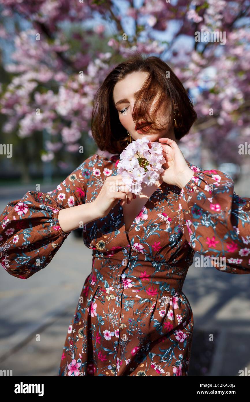 A spectacular woman in a bright dress stands against the background of ...