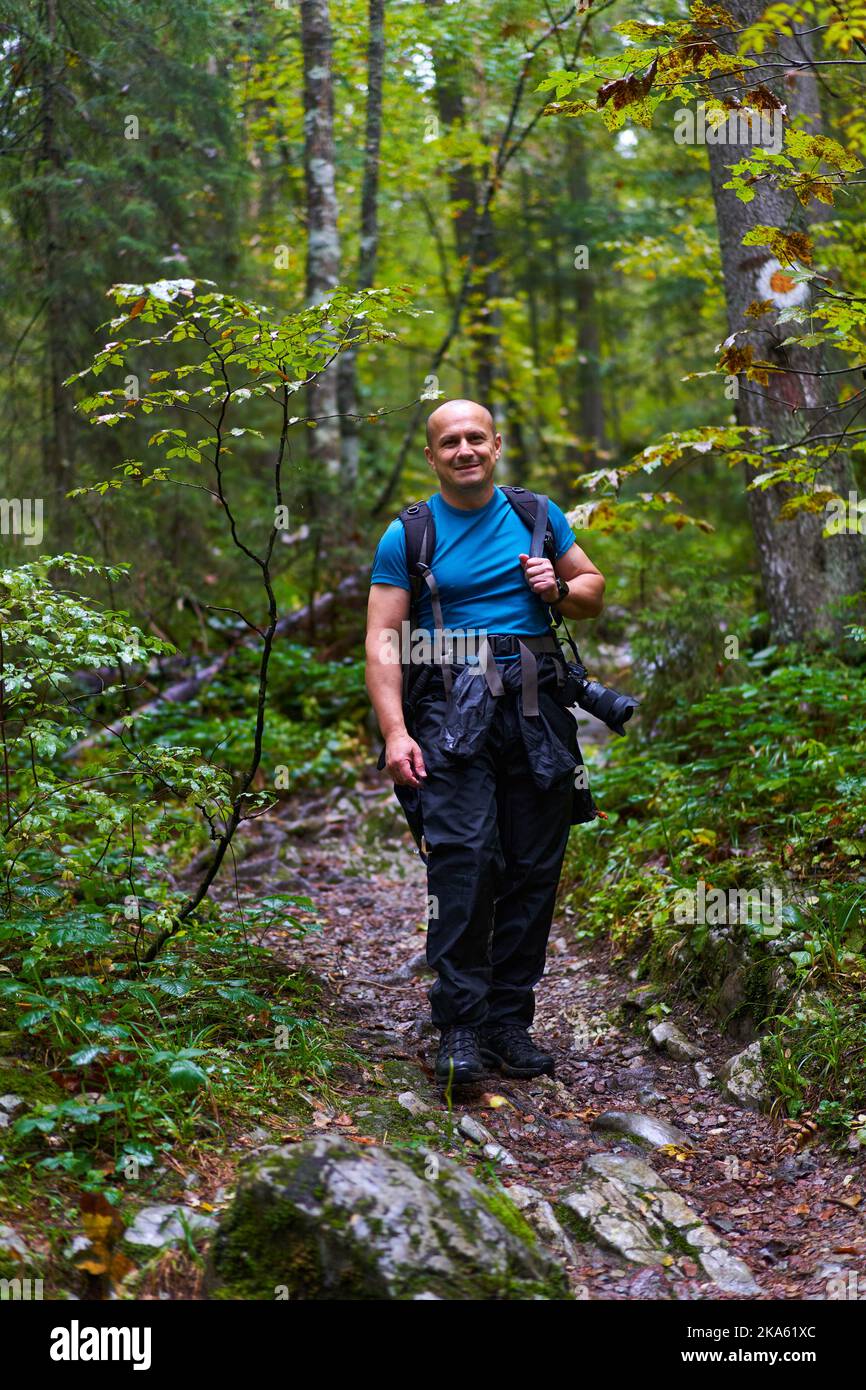 Nature photographer with heavy backpack and camera hiking into the pine ...