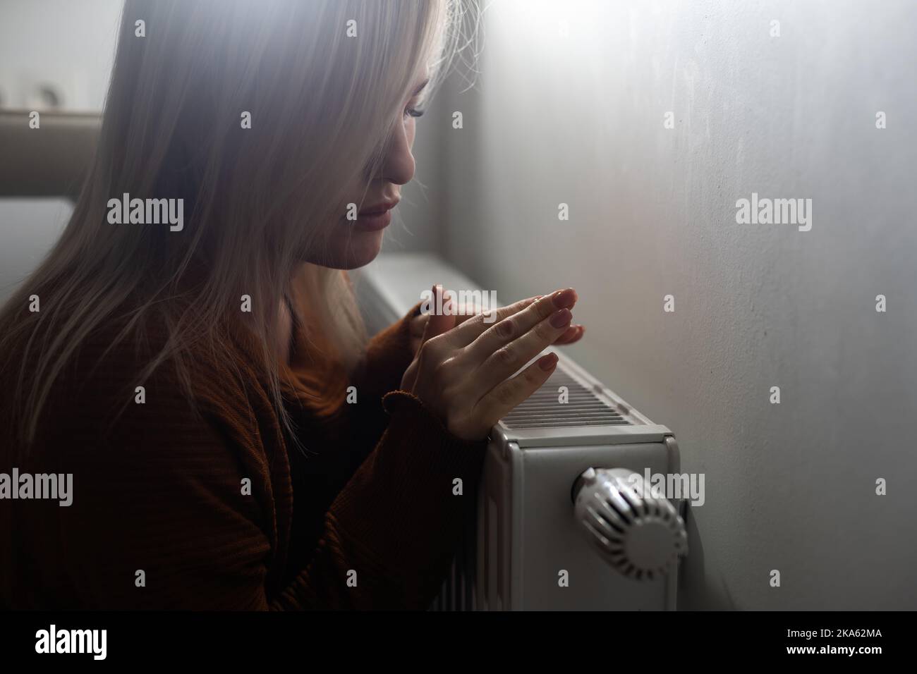 Closeup of woman warming her hands on the heater at home during cold ...