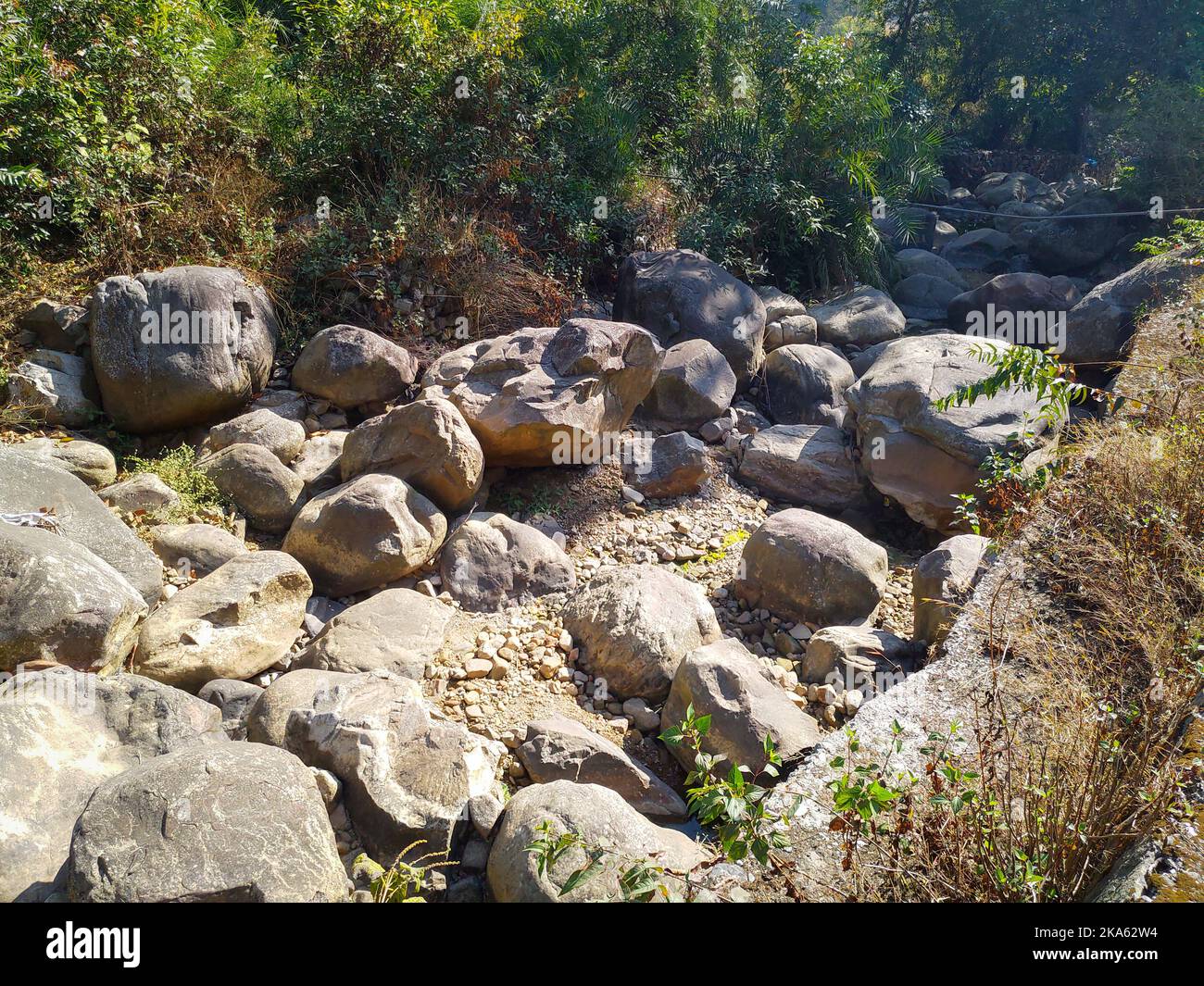 Dry river bed filled with large rolling stones with mountains in the ...