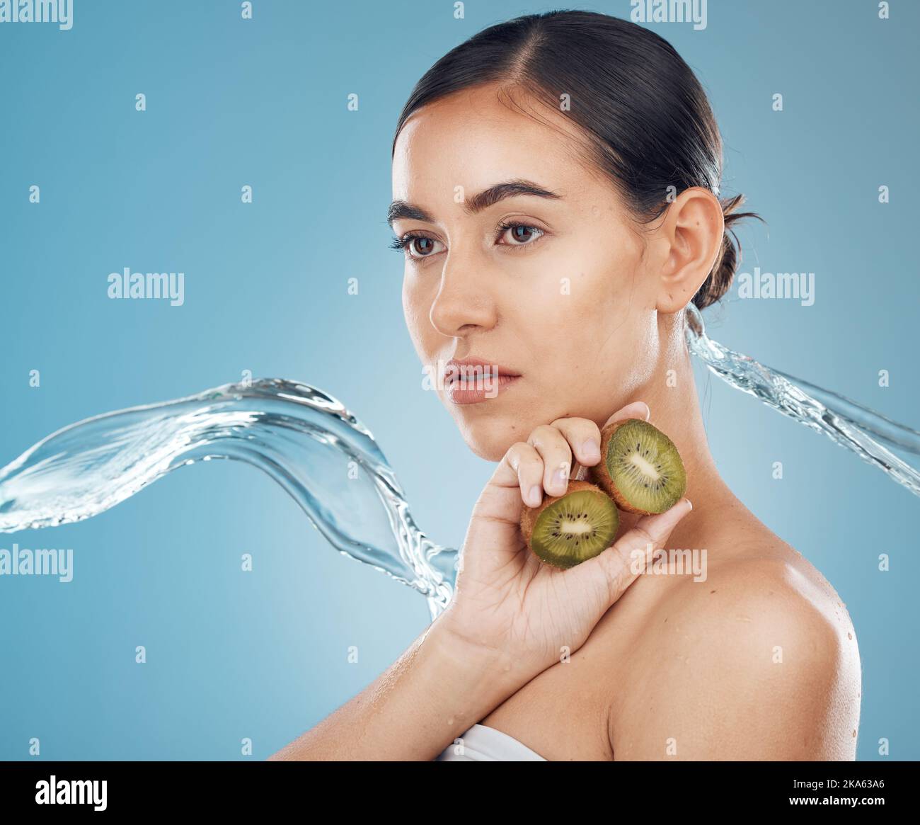 Beauty, water and kiwi with a model woman in studio on a blue ...