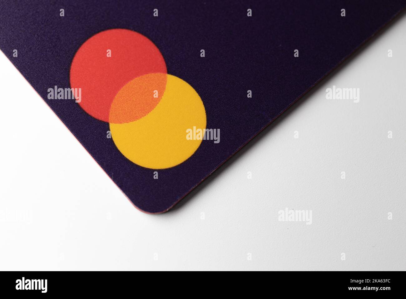 The Mastercard logo on a purple bank card, seen while placed on a white ...