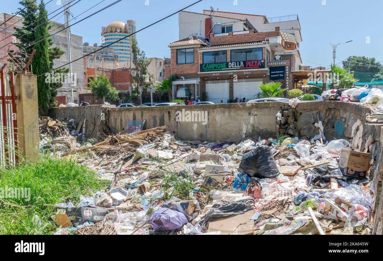 Scattered trash can near garbage bins and a pizza restaurant the ...