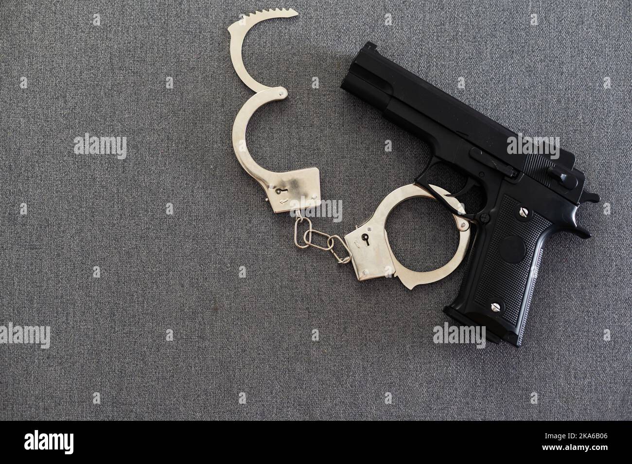 Black gun and metal handcuffs lie on the black background. Private ...