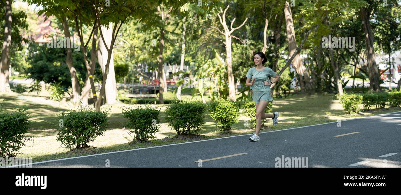 Asian woman runners. She was running on the park in the morning. banner ...