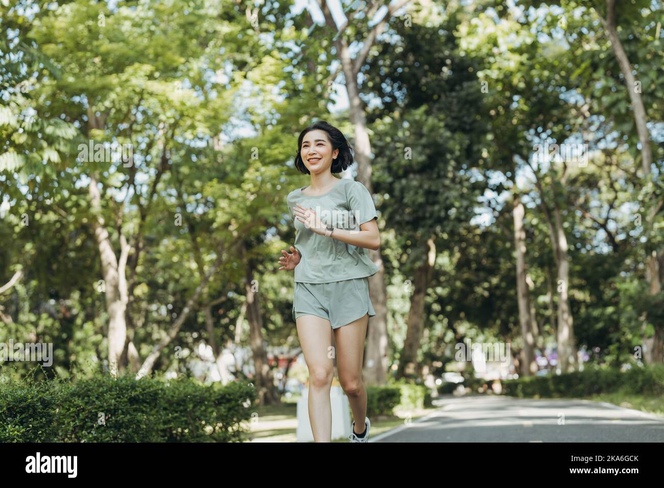 Happy athletic asian woman runners. She was running on the park in the ...
