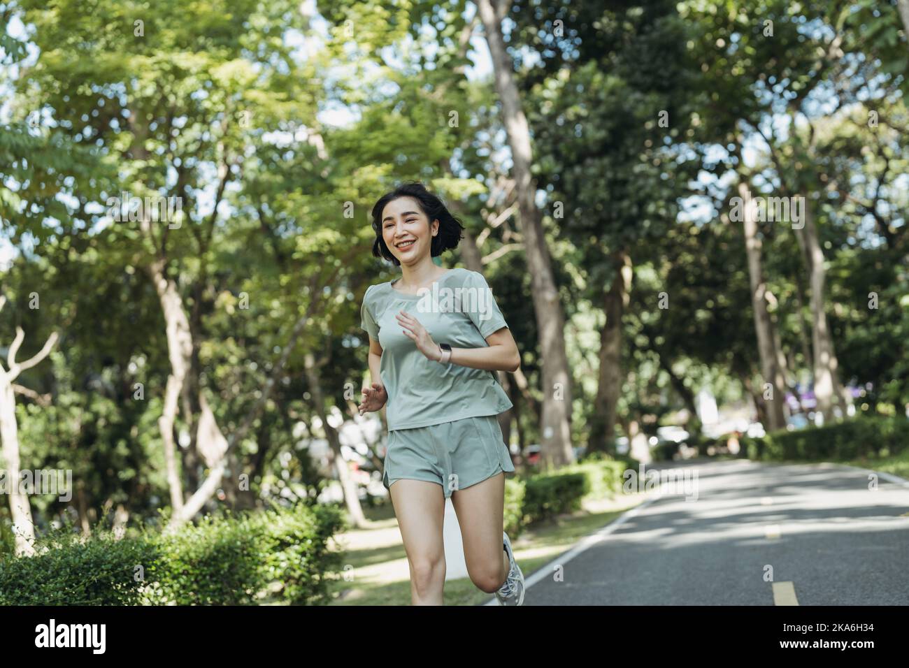 Happy athletic asian woman runners. She was running on the park in the ...