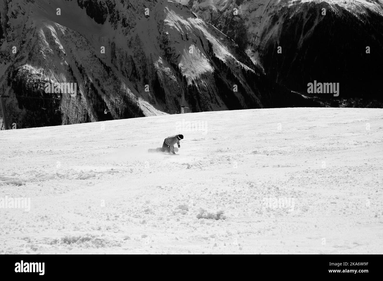 Snowboarder downhill on ski slope in high snowy mountains at winter day ...