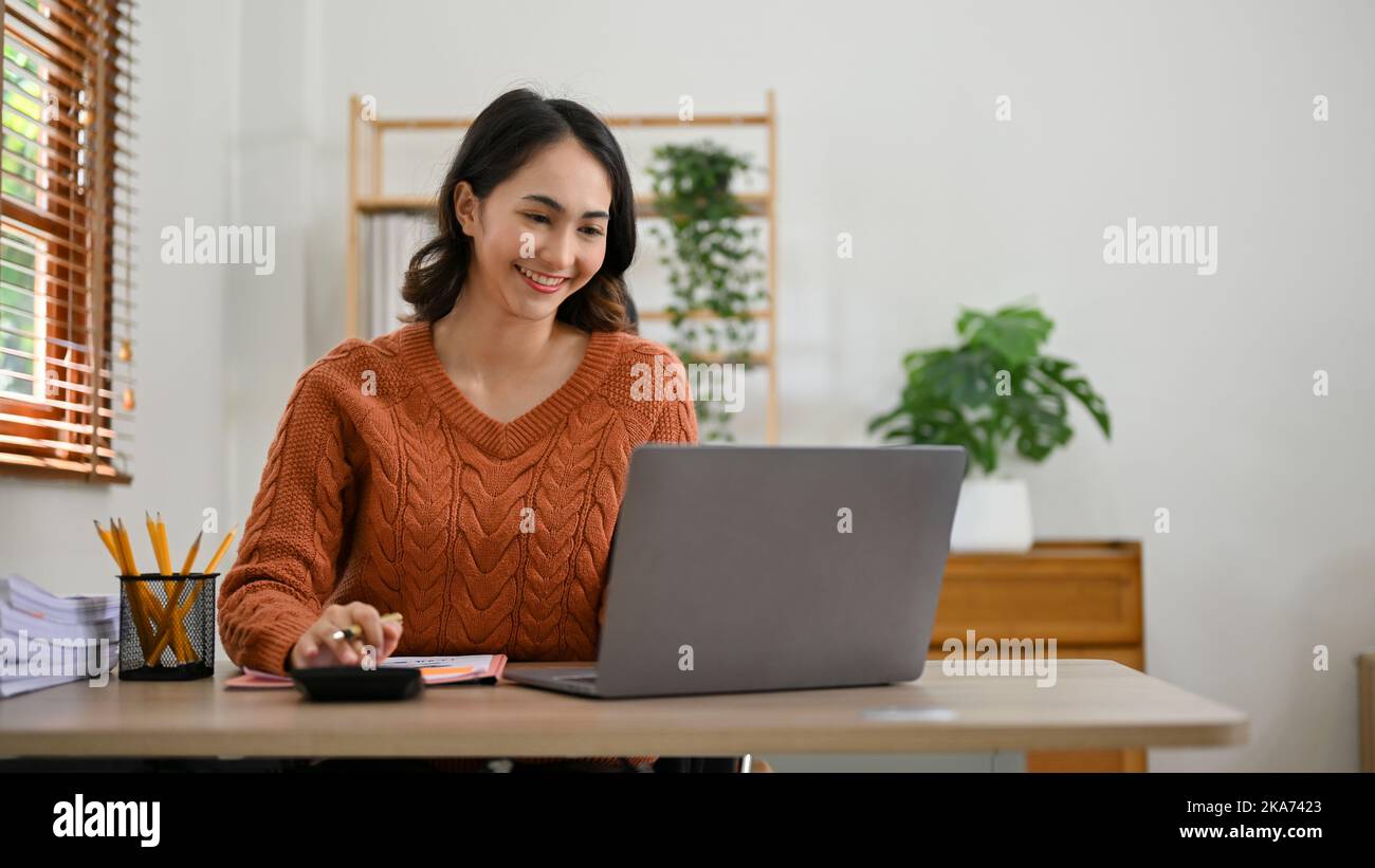 Attractive millennial Asian businesswoman working at her desk, checking ...