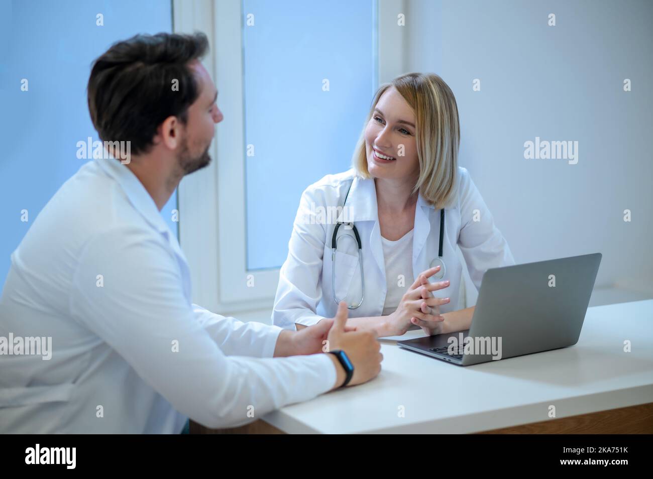 Two people in lab coats discussing something and looking interested ...