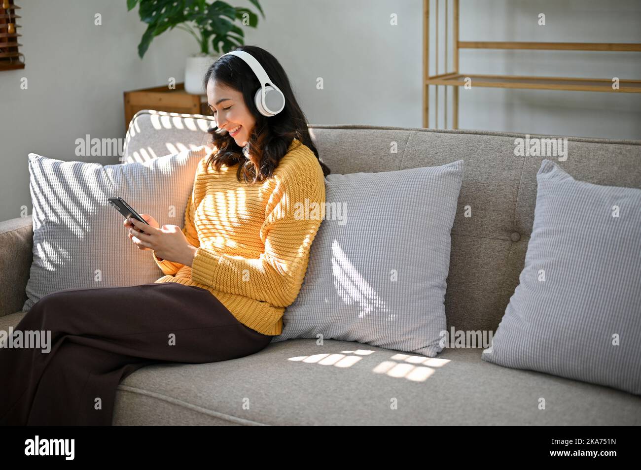 Happy charming young Asian female in casual clothes spending her ...