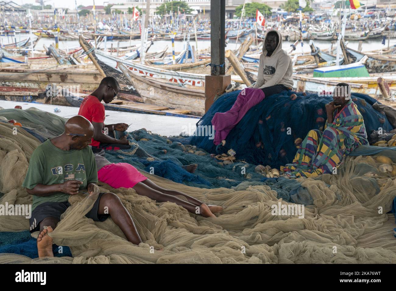 Accra, Ghana 20190601. Fishermen repair yarns in the port city of Tema ...
