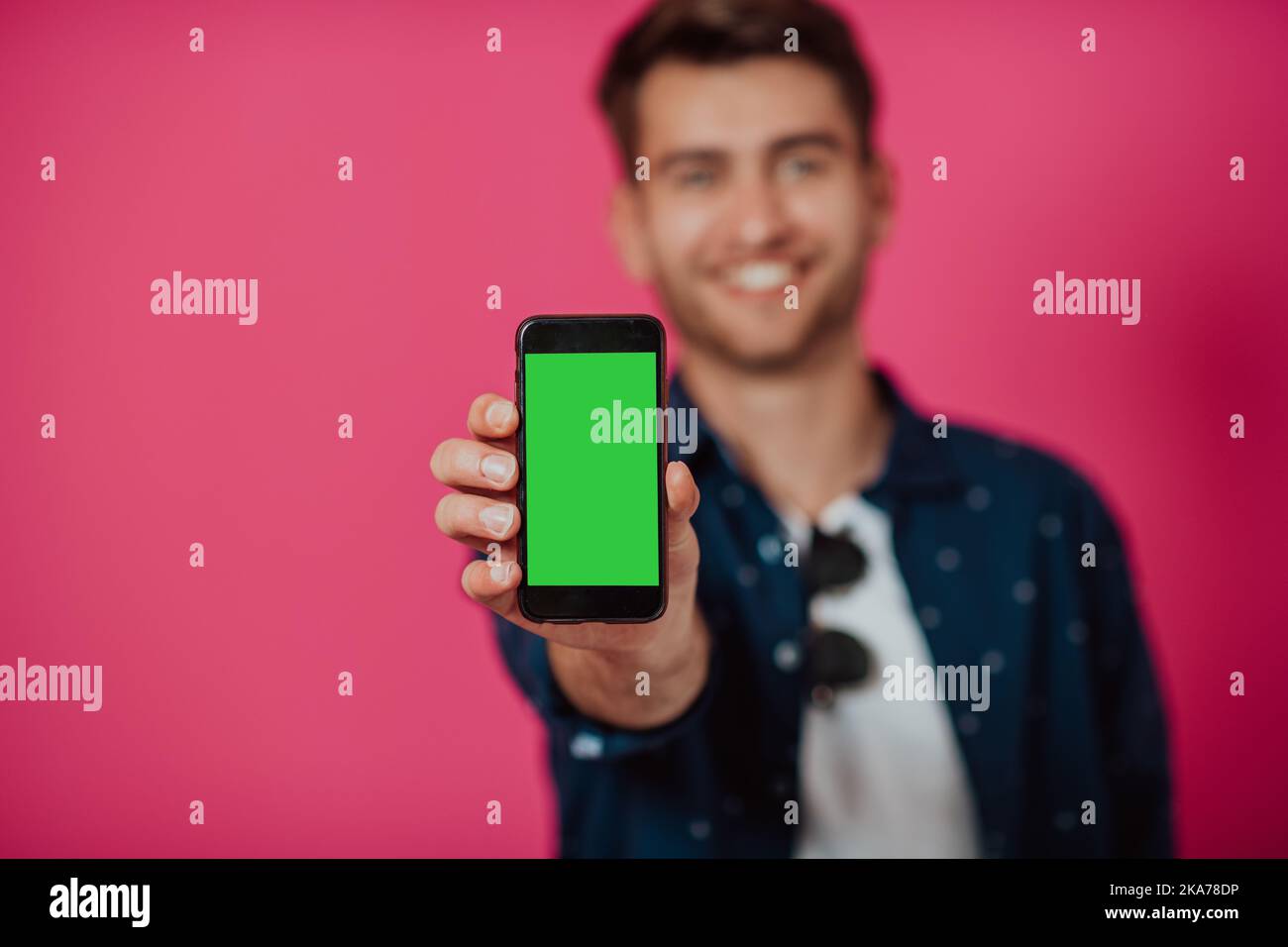 Portrait of a happy man using smartphone isolated over pink background ...
